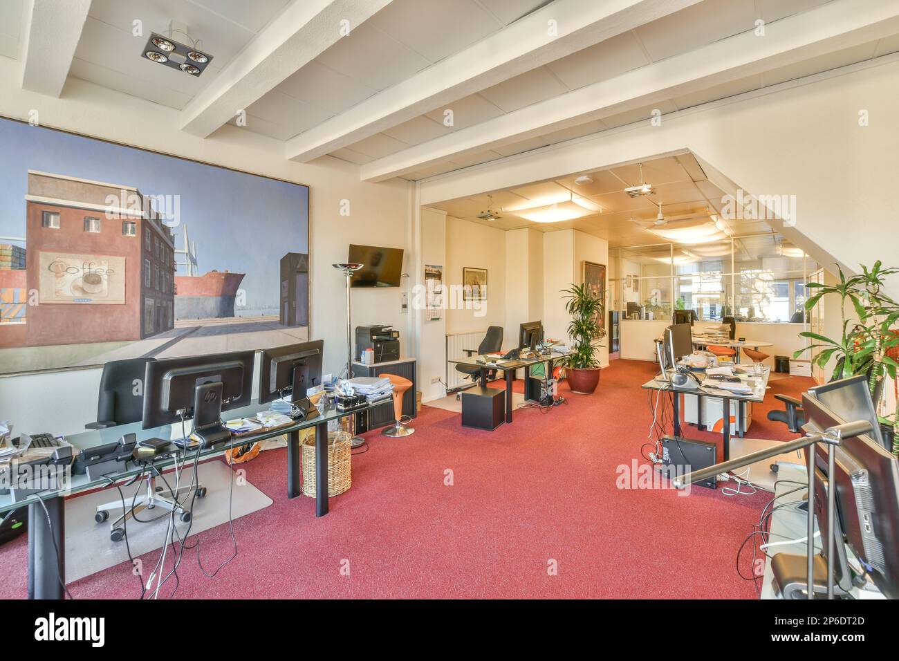 a living room with red carpet and two computers on the desks in front ...