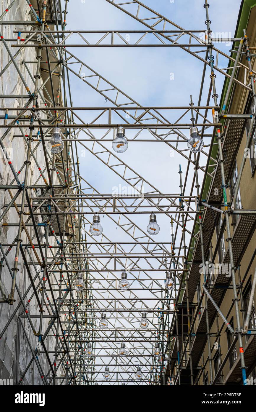 Scaffolding over a narrow street with lanps hanging underneath Stock ...