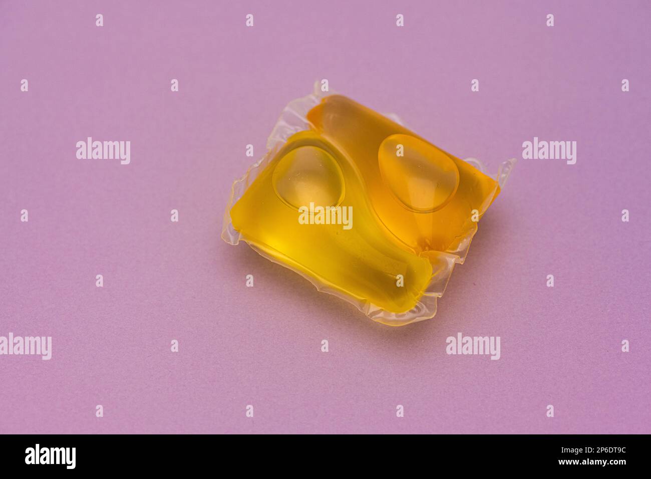 Yellow washing detergent capsule on purple table Stock Photo - Alamy