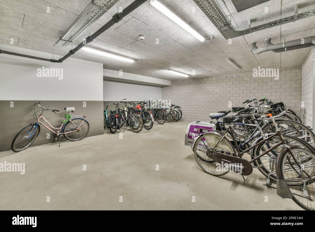 some bikes parked in a bike parking area with white walls and gray ...