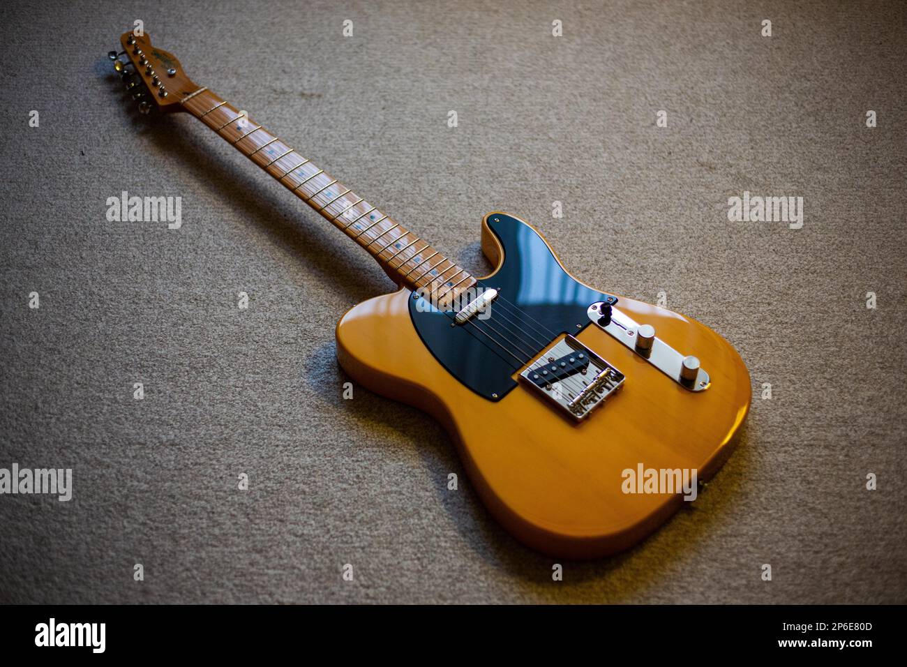 A vibrant yellow electric guitar with a sleek black handle on a ...