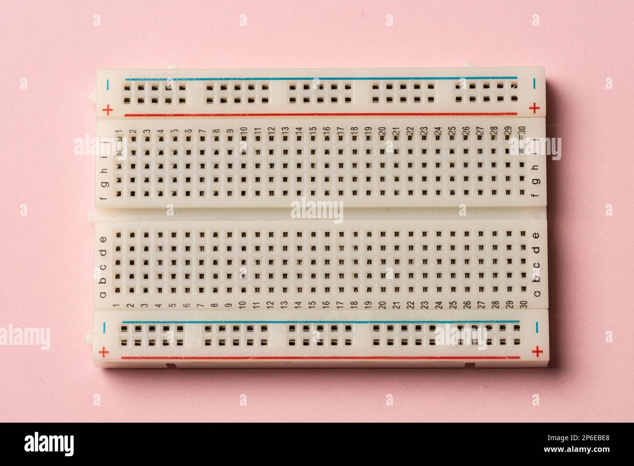 An electronics breadboard on pink background Stock Photo - Alamy