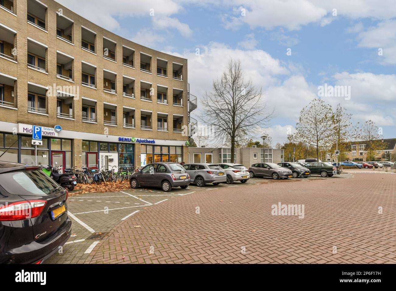 a parking area with cars parked on the side and buildings in the back ...