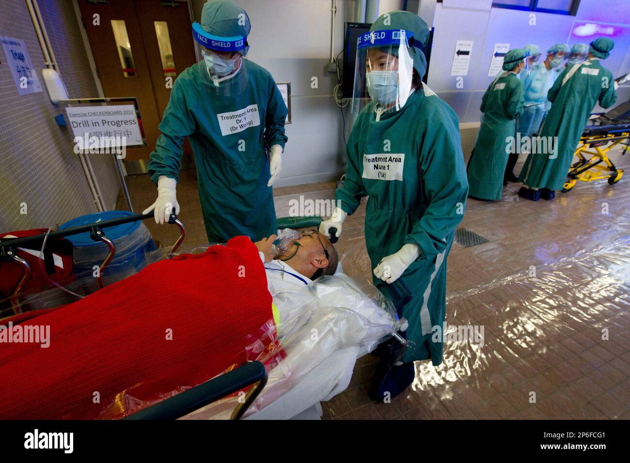 Hospital workers wearing protective gear push a man acting as a patient ...