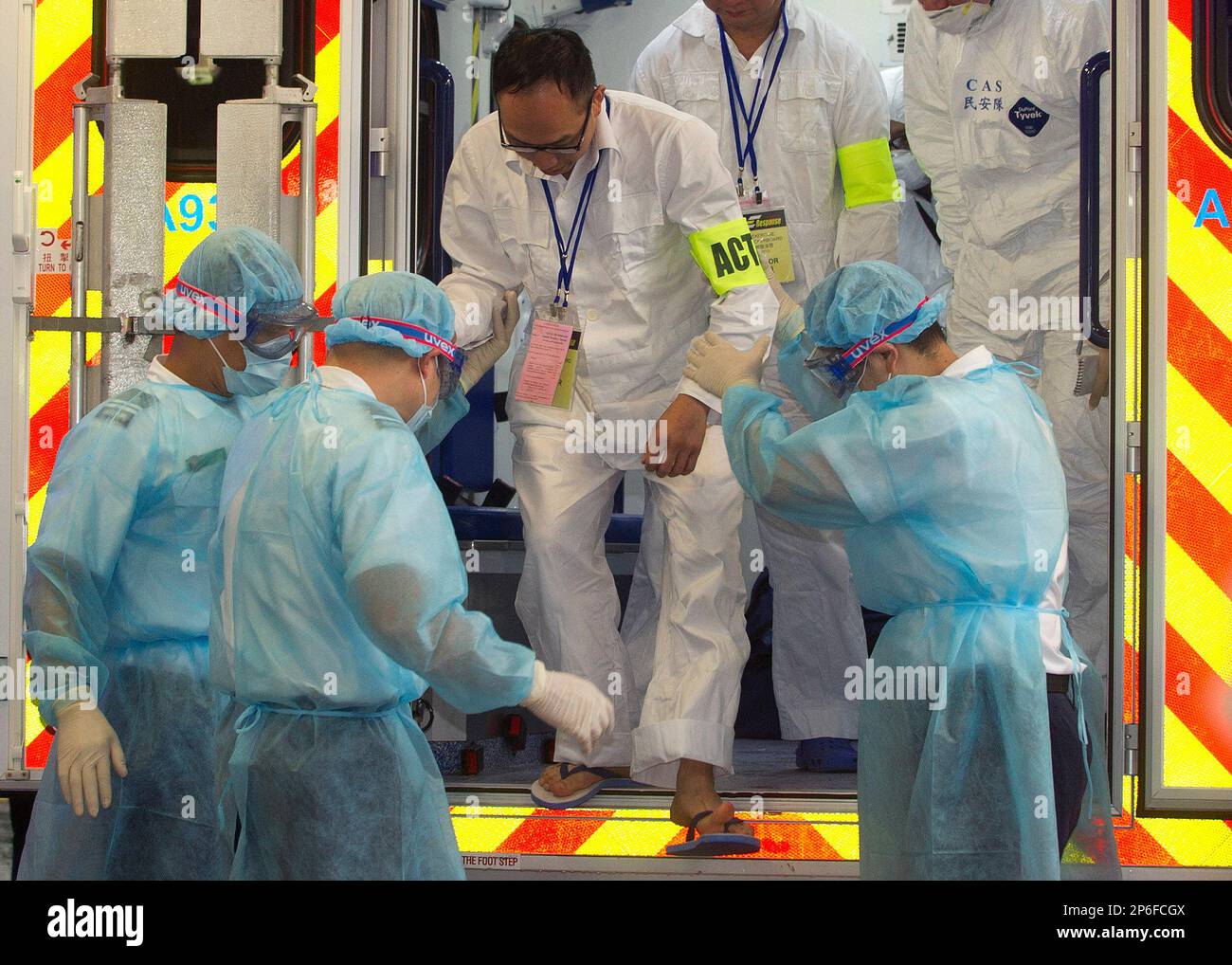 Hospital workers wearing protective gear assists a man acting as a ...