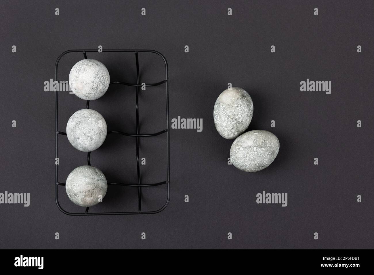 Grey Easter eggs in a black stand on a black background. Minimal Easter ...