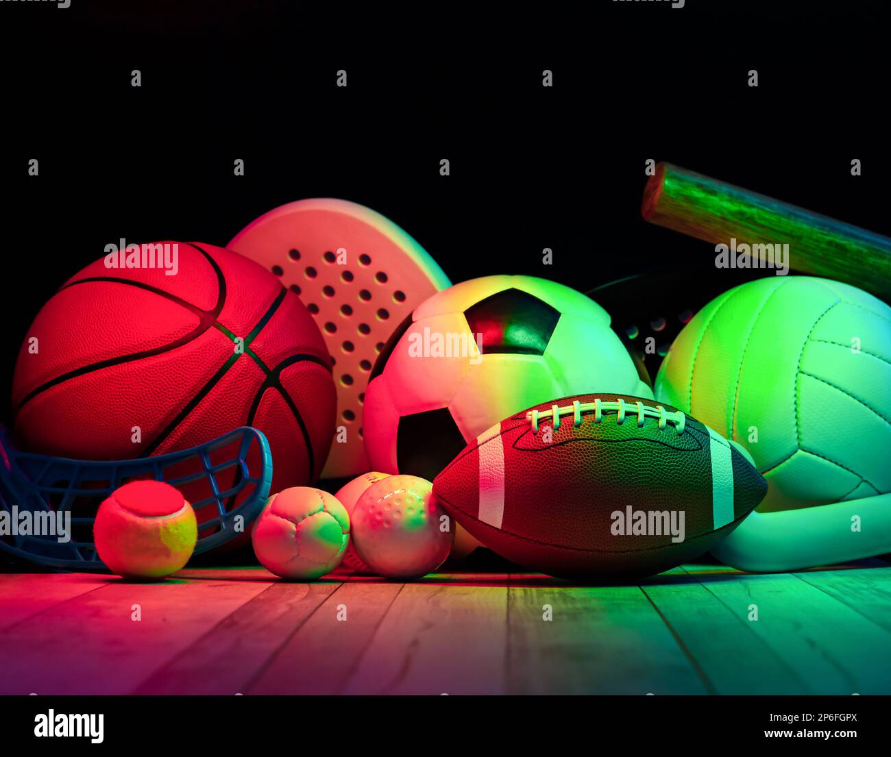 Sports equipment, rackets and balls on hardwood court floor with neon ...
