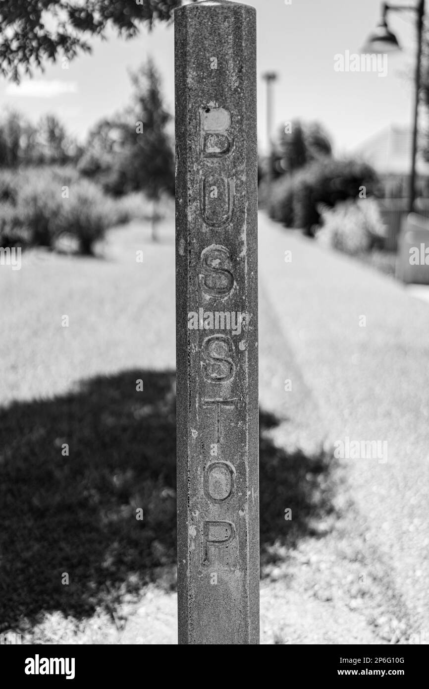 A greyscale vertical image of an old rusty sign that says "Bus Stop ...