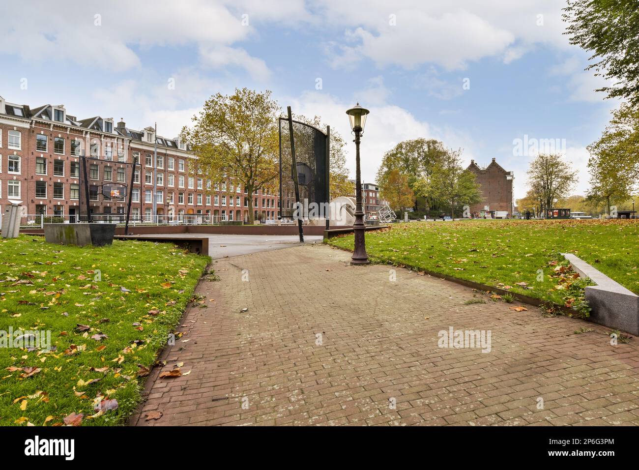 a brick path in the middle of a park with leaves on the ground and ...