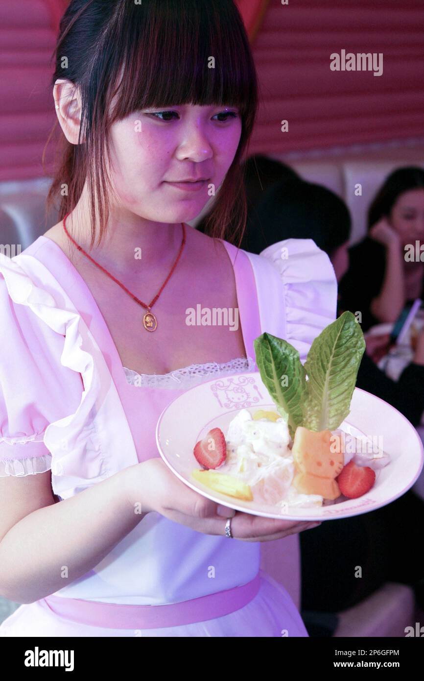A waitress dressed as maidservant serves customers at the theme ...