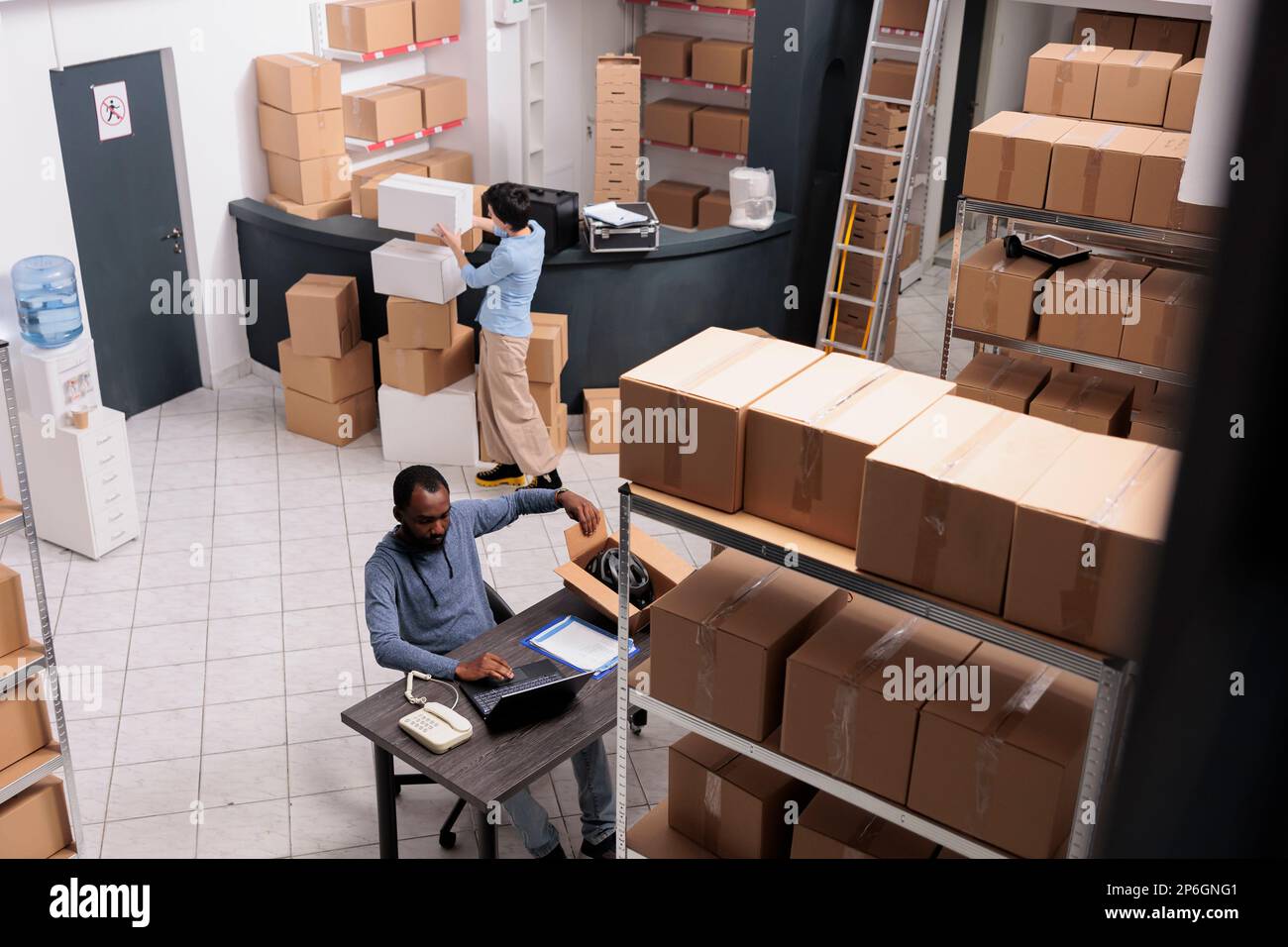 Top view of storehouse supervisor checking shipping logistics on laptop computer while preparing ...