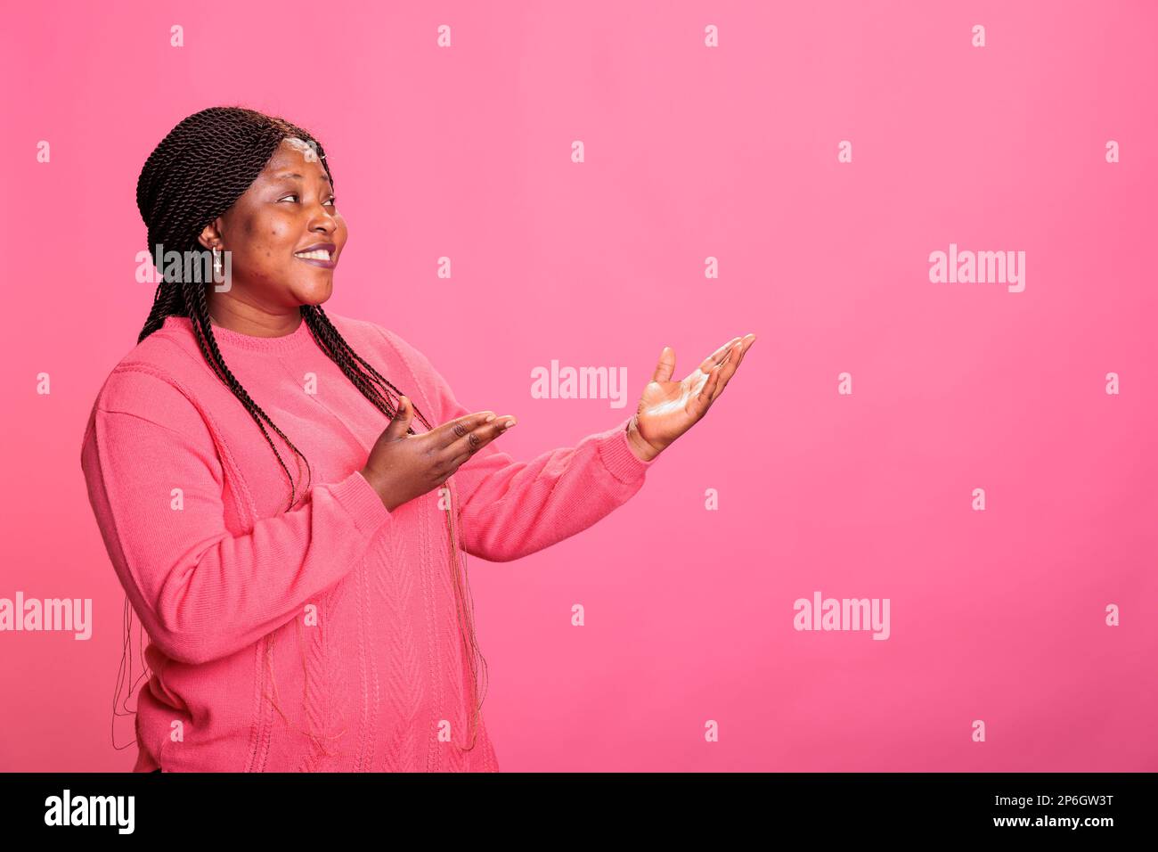 Portrait of smiling woman advertising promotional product in studio ...