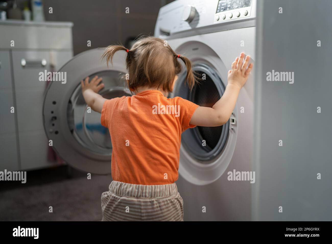 One girl small caucasian toddler child daughter standing at the washing ...