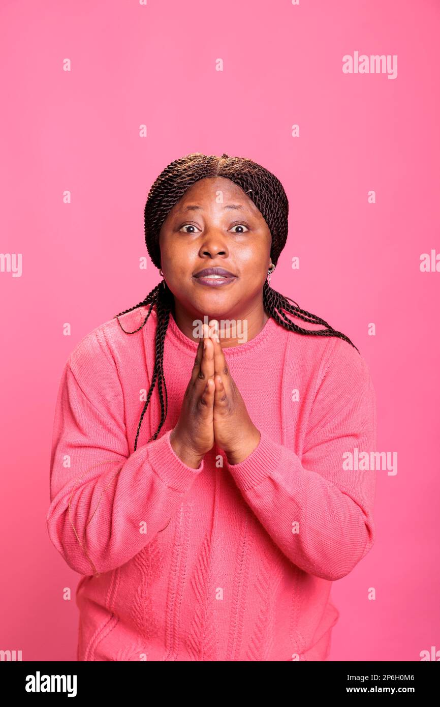 African american woman doing prayer hands symbol in studio, showing ...