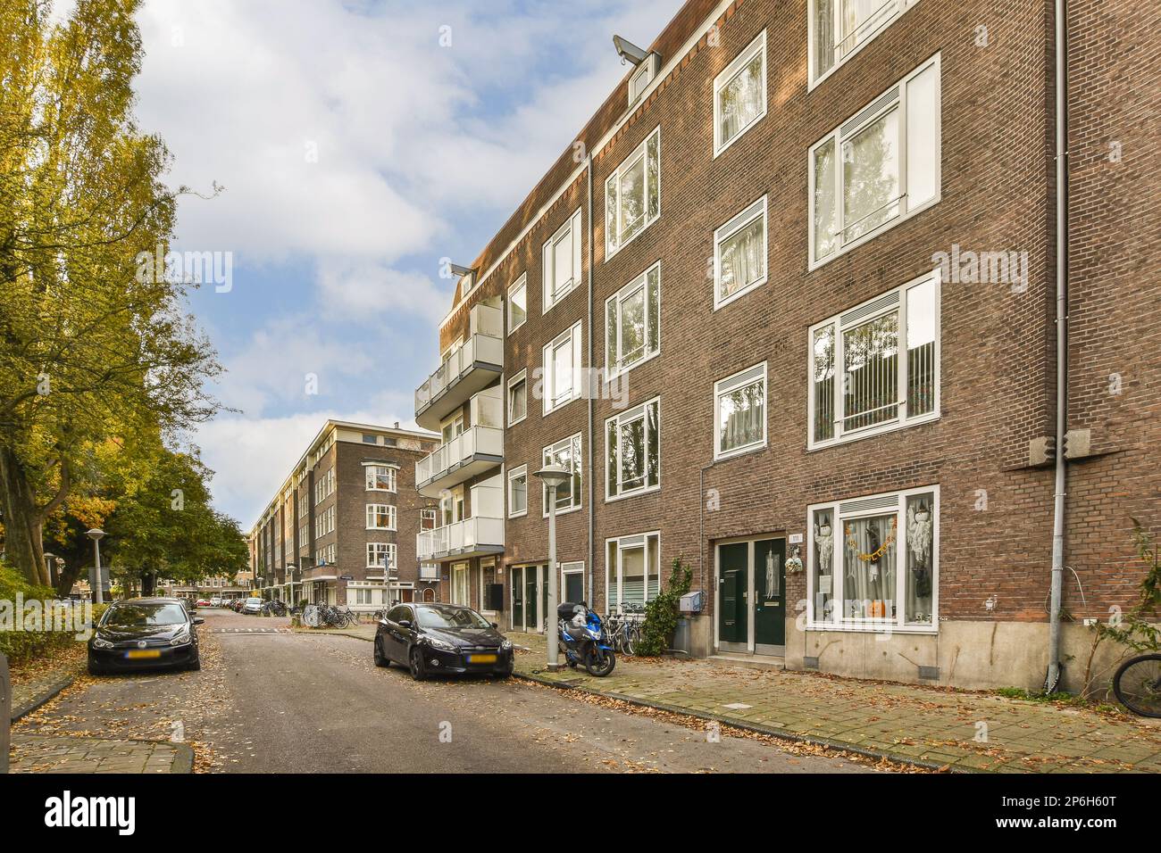 a city street with cars parked on the side and trees lining the street ...