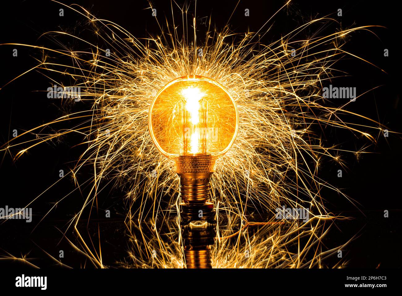 Isolated lighted up incandescent lamp with fire sparks and filament in ...