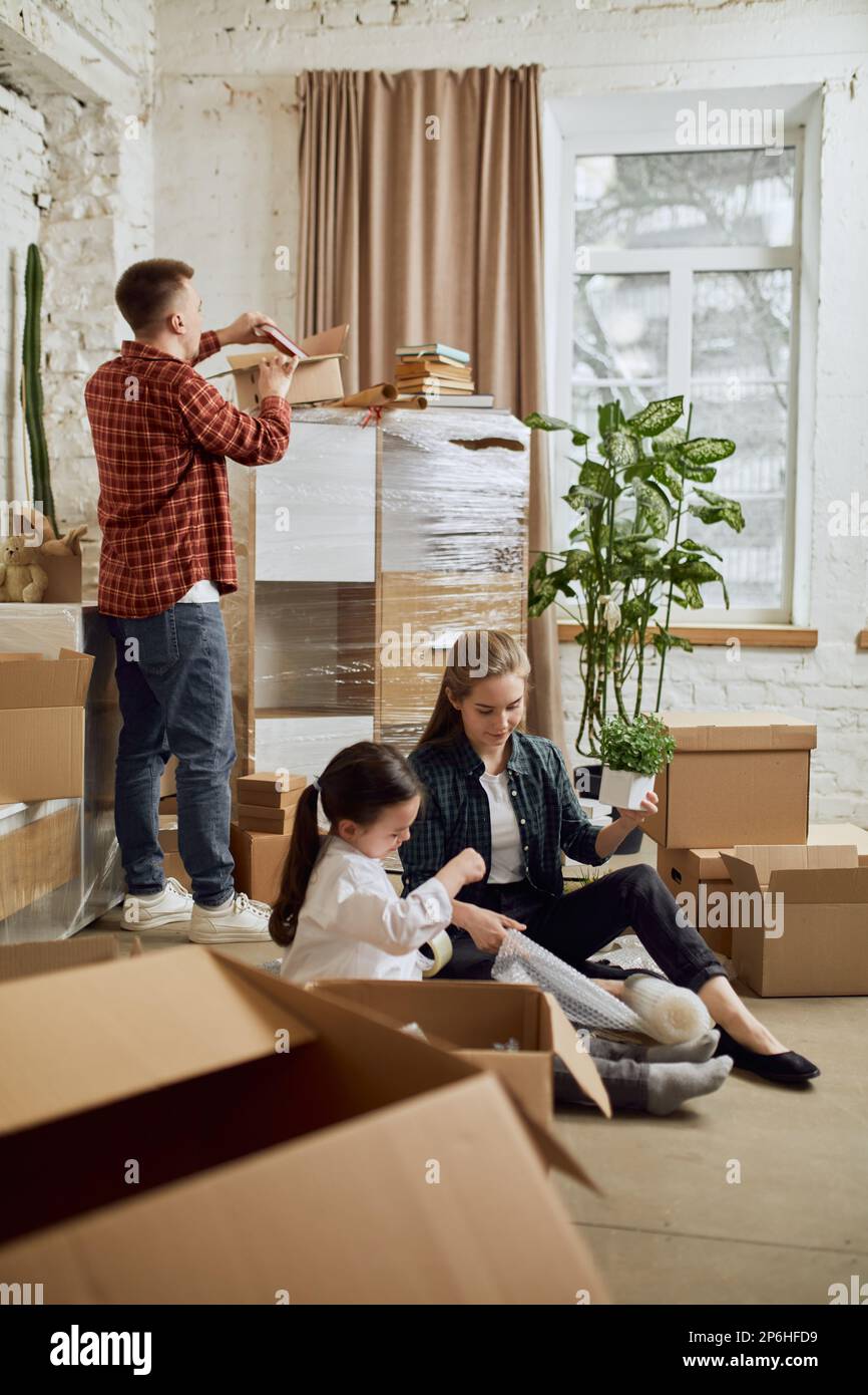 Young happy family, man, woman and kid moving into new flat, apartment ...