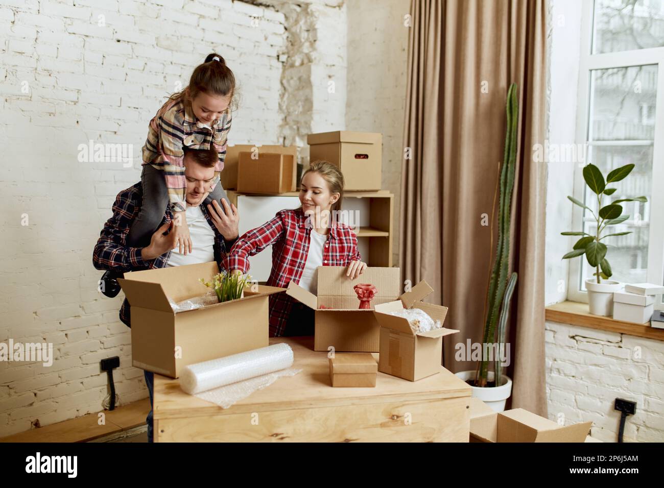 Putting stuffs on place, furnishing. Young happy family, man, woman and ...