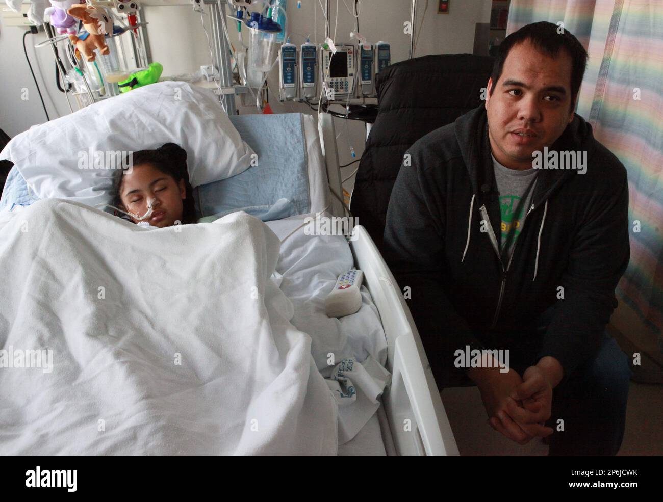 John Bowman sits by the side of his seriously injured daughter, Amina ...