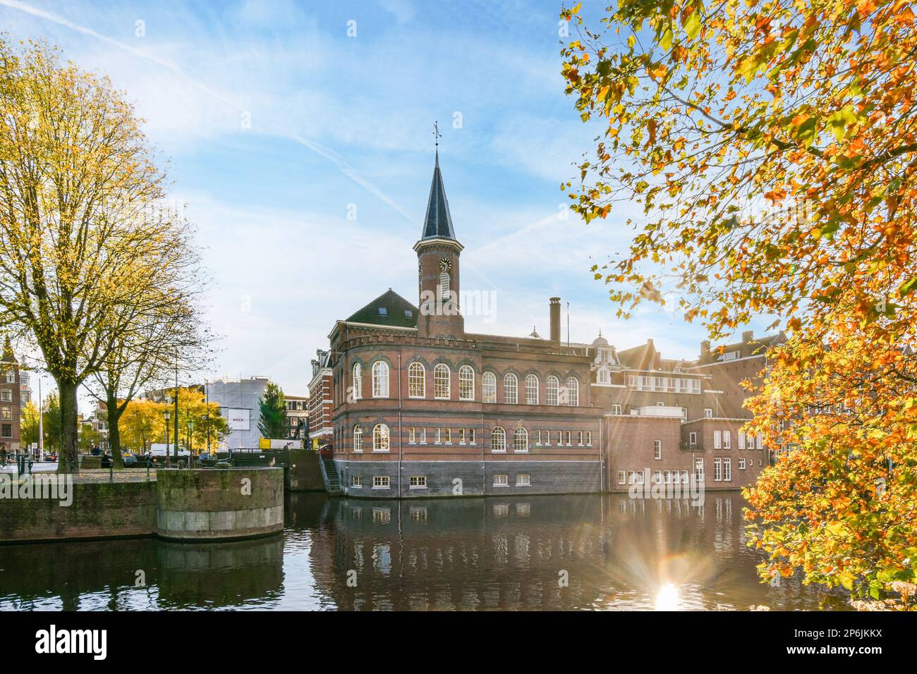 an old brick building on the side of a river with autumn leaves in ...