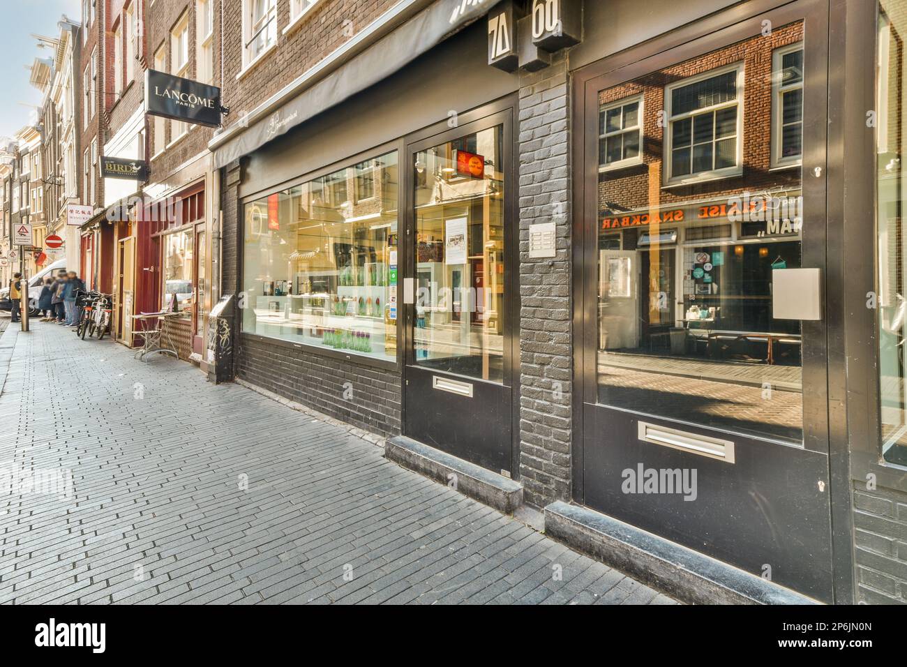 an empty city street with people walking on the sidewalk and buildings ...