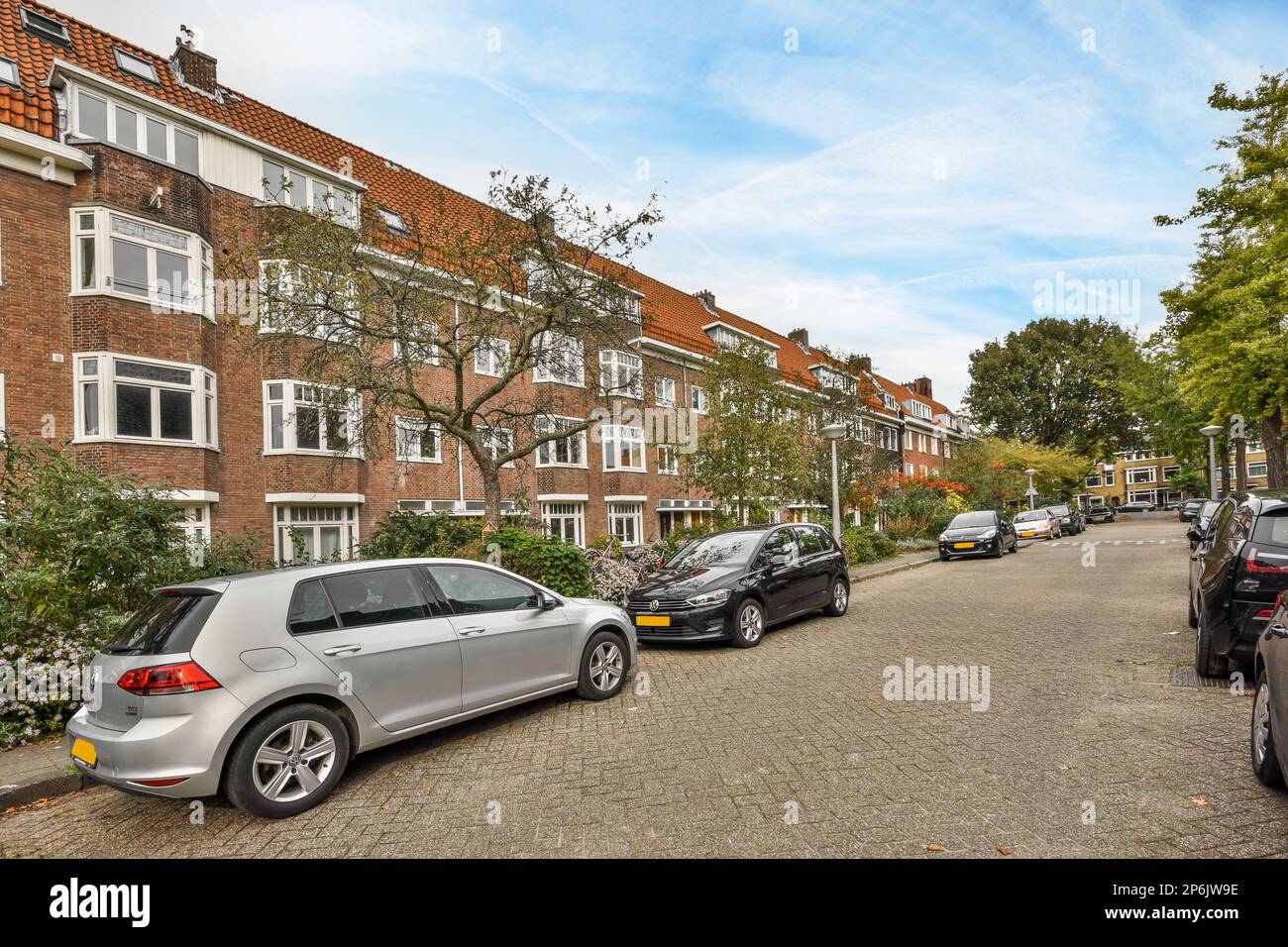 cars parked on the side of a street in front of a brick building with ...