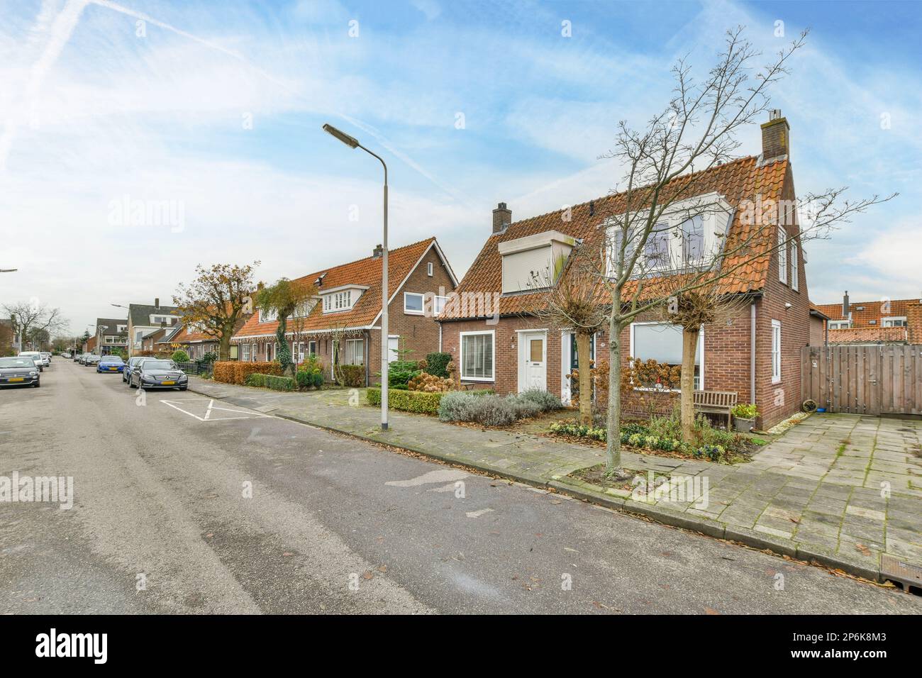 a street with houses and cars parked on the side of the road next to ...