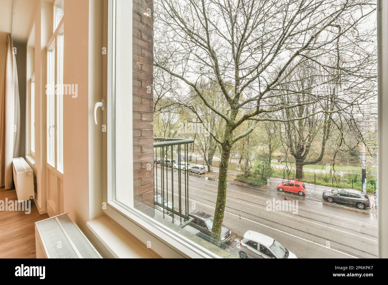 a tree outside the window with no leaves on it and cars parked in the ...