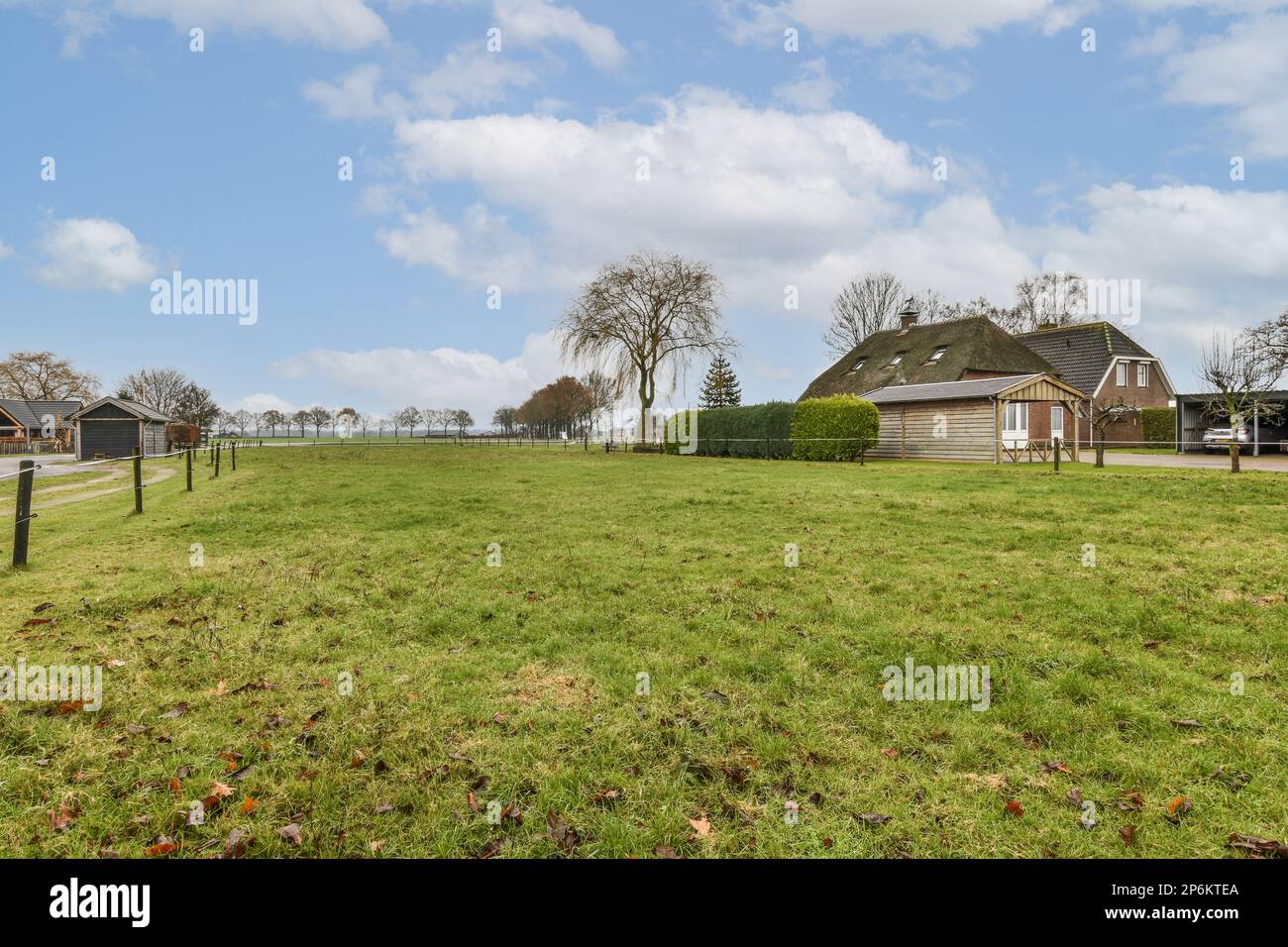 a grassy field with houses in the distance and trees on the other side ...