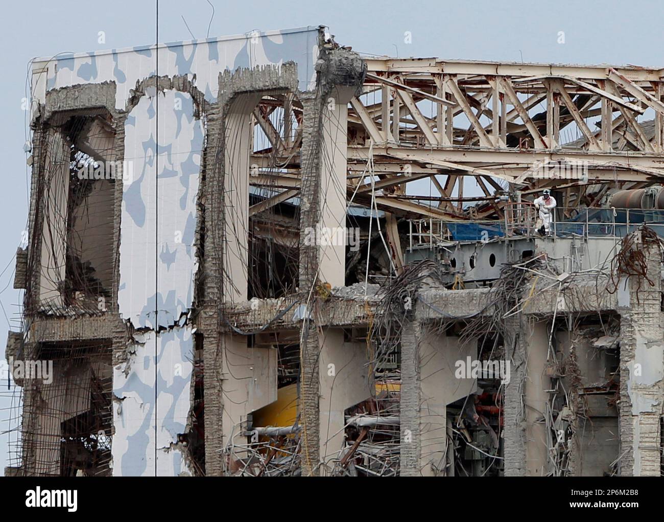 A worker wearing protective suit and mask works atop of destroyed unit ...
