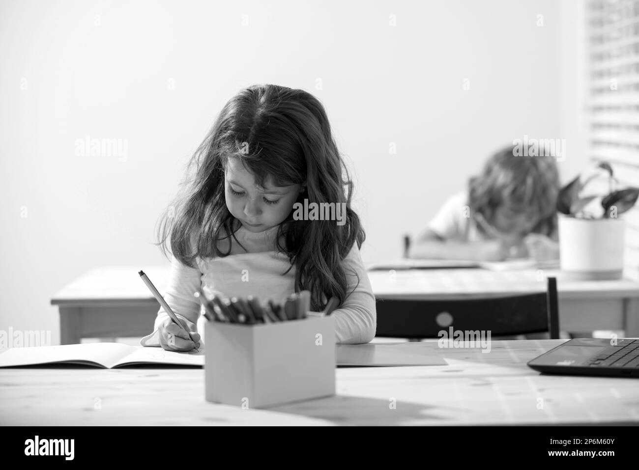 Back to School. Cute pupil writing at desk in classroom at the ...
