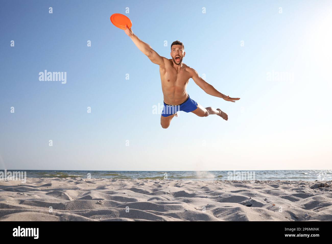 Sportive man jumping and catching flying disk at beach Stock Photo - Alamy