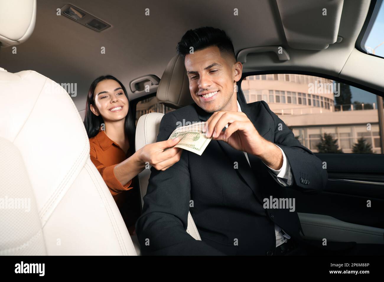 Young woman giving money taxi driver in modern car Stock Photo - Alamy