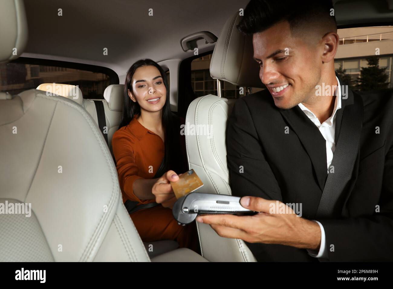 Young woman paying for service using credit card via payment terminal ...