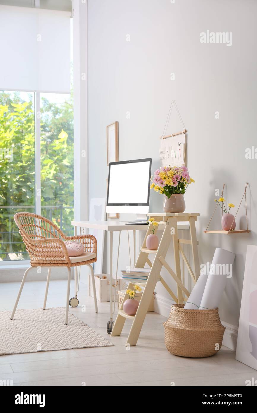 Comfortable workplace with modern computer and flowers in room ...