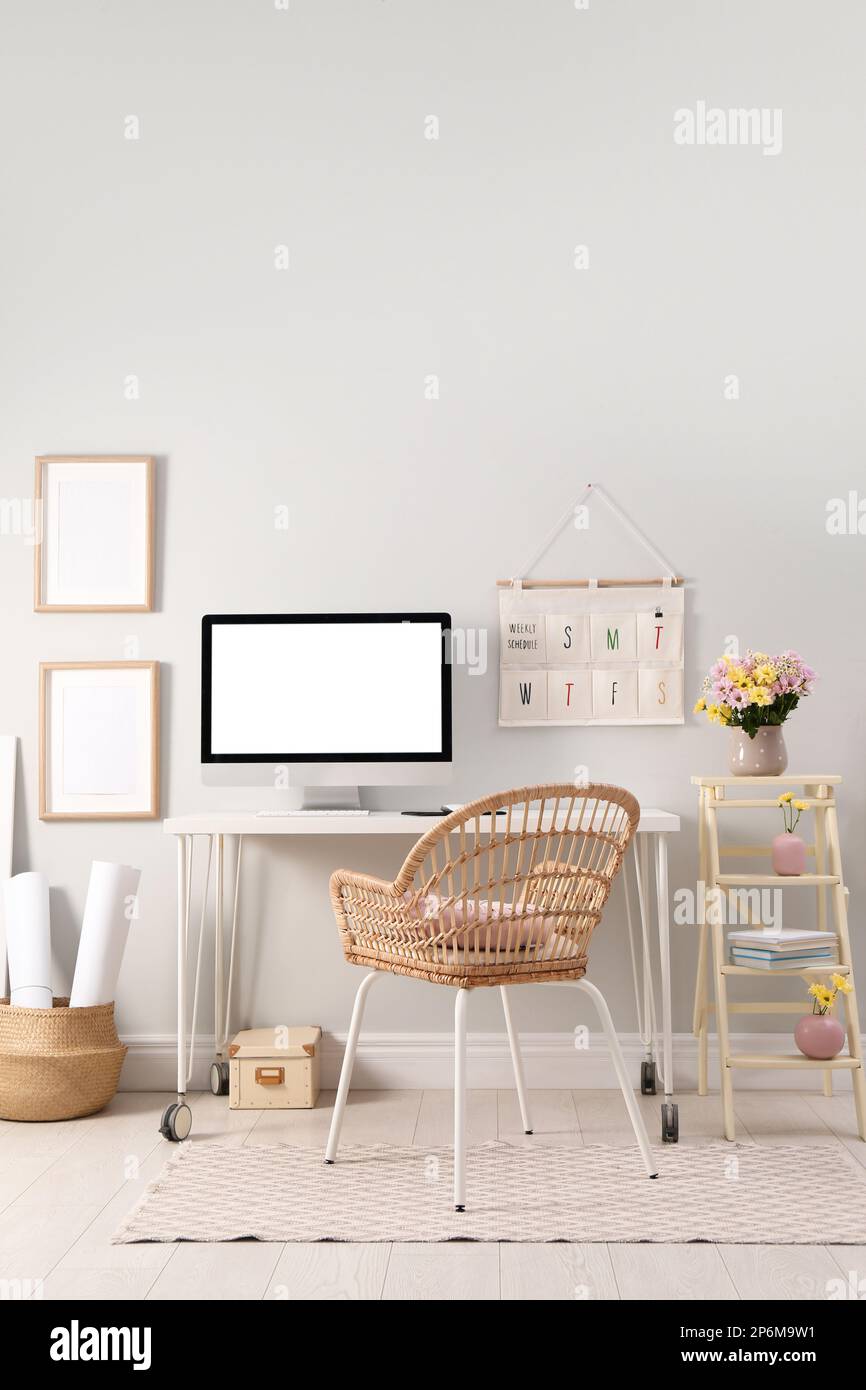 Comfortable workplace with modern computer and flowers in room ...