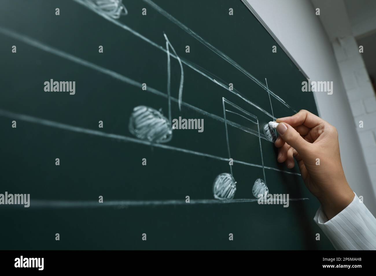 Teacher writing music notes with chalk on greenboard, closeup Stock ...