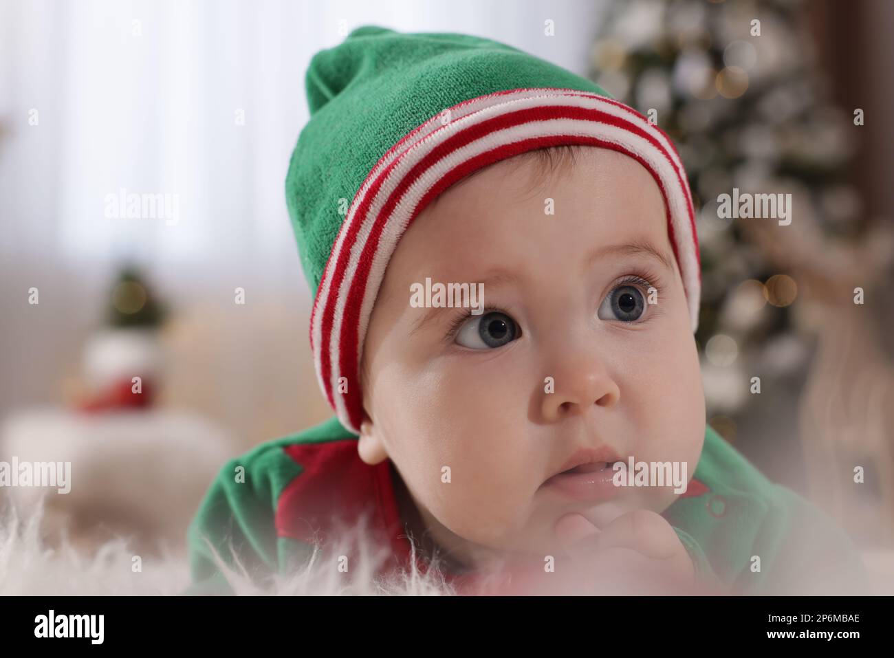 Baby wearing cute elf costume in room decorated for Christmas Stock ...
