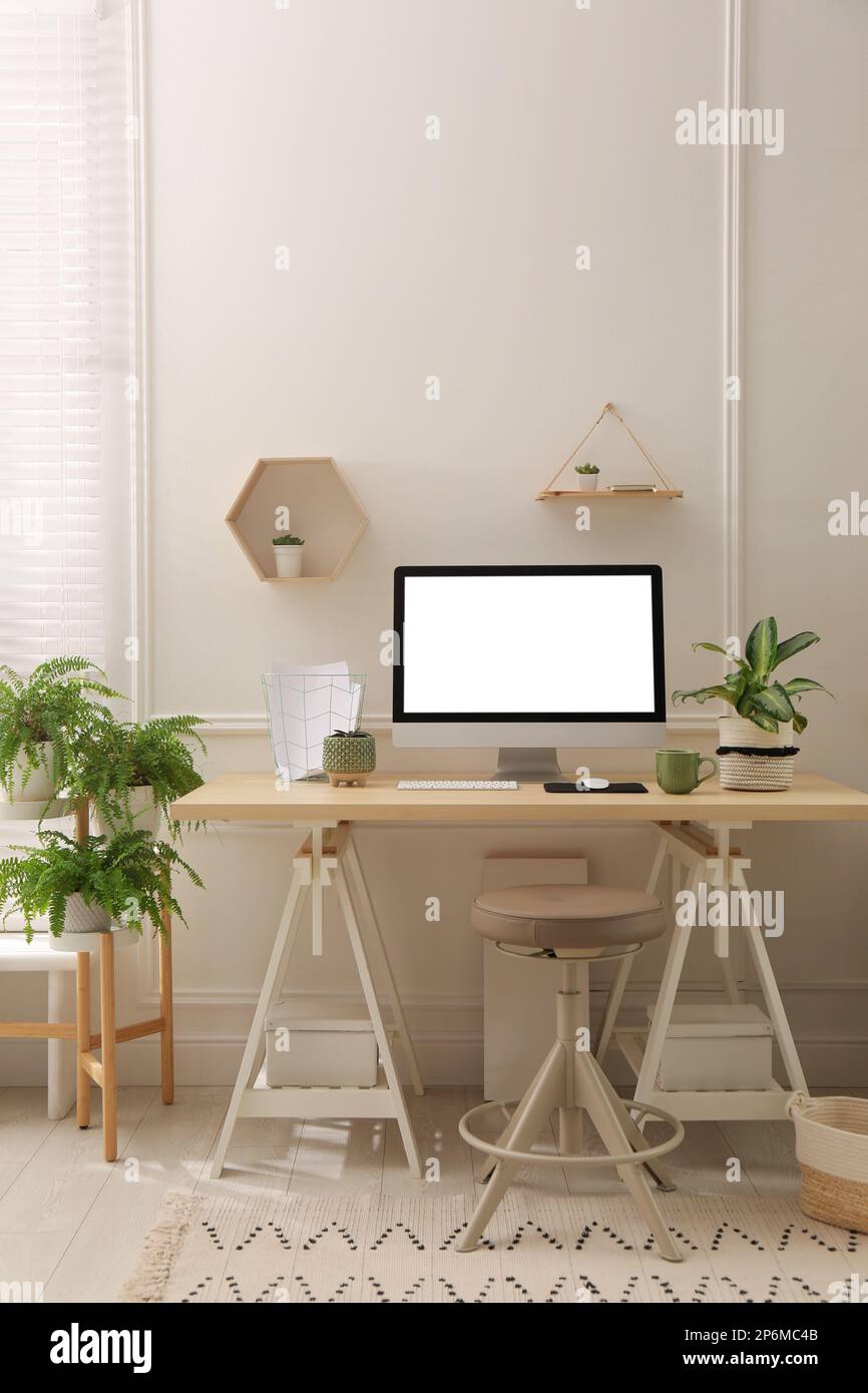 Comfortable workplace with modern computer and houseplants in room ...