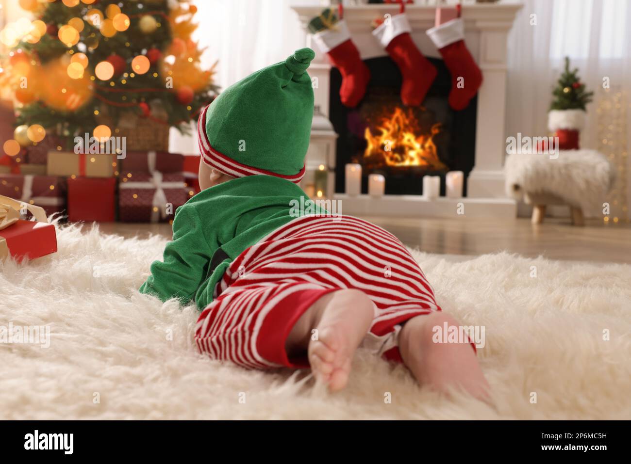 Baby wearing cute elf costume in room decorated for Christmas Stock ...