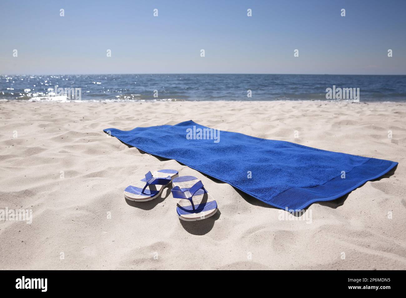 Flip flops and blue beach towel on sandy seashore Stock Photo - Alamy