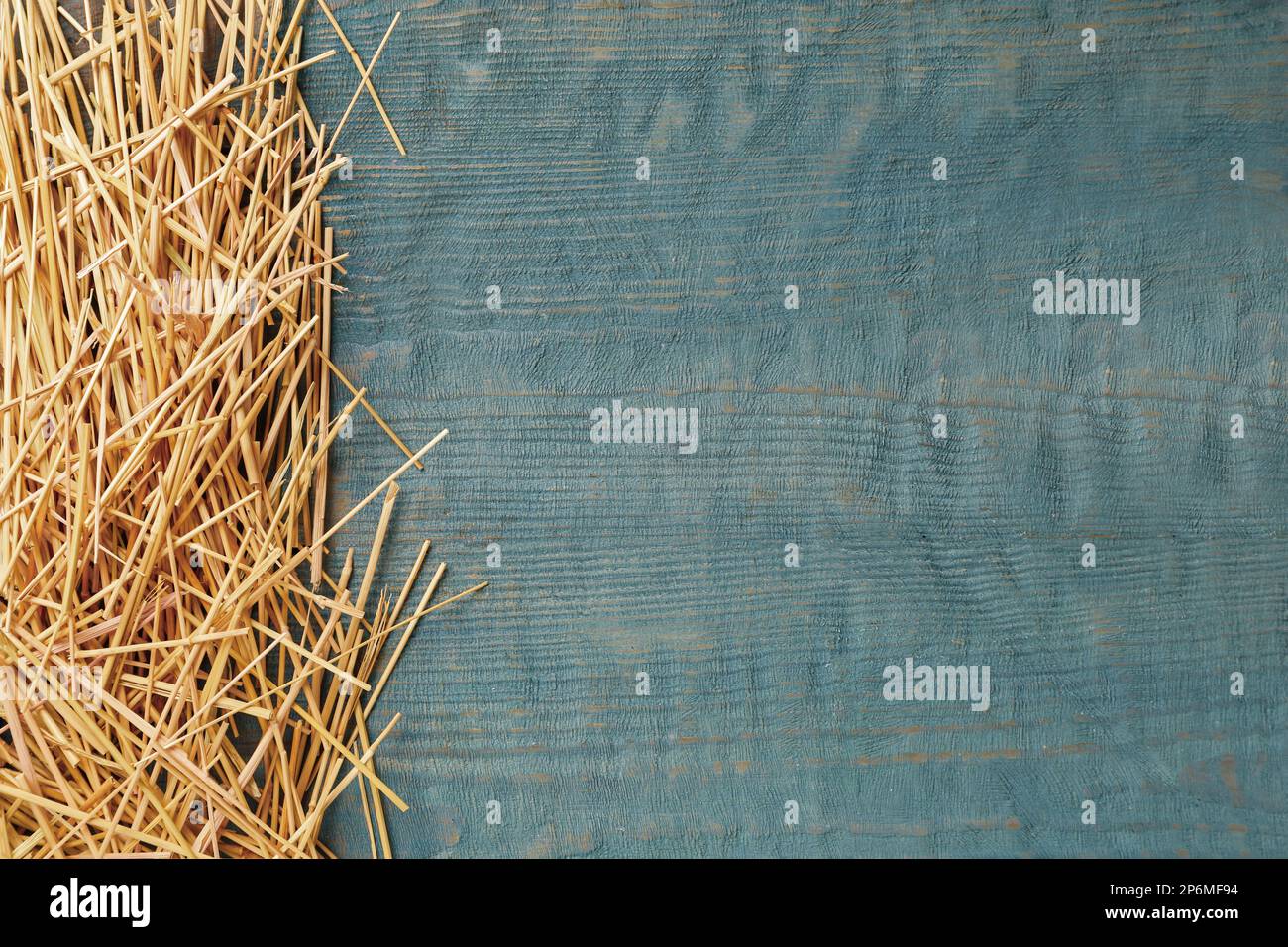 Heap of dried hay on light blue wooden background, flat lay. Space for ...