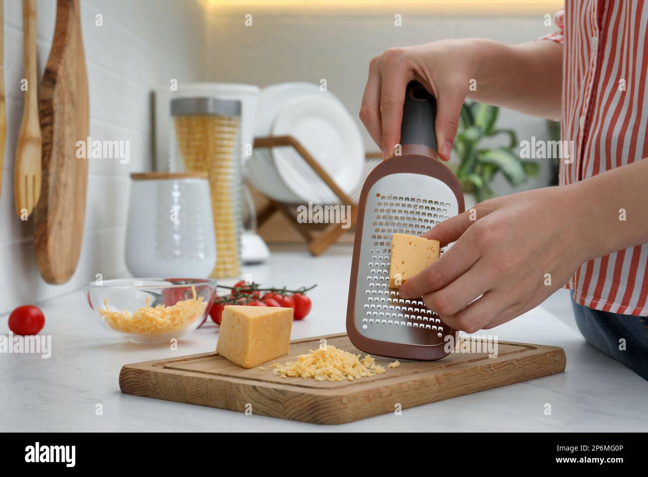 Woman grating cheese at kitchen counter, closeup Stock Photo - Alamy