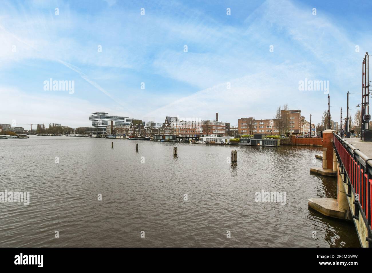 a river with buildings on the other side and blue sky in the photo is ...