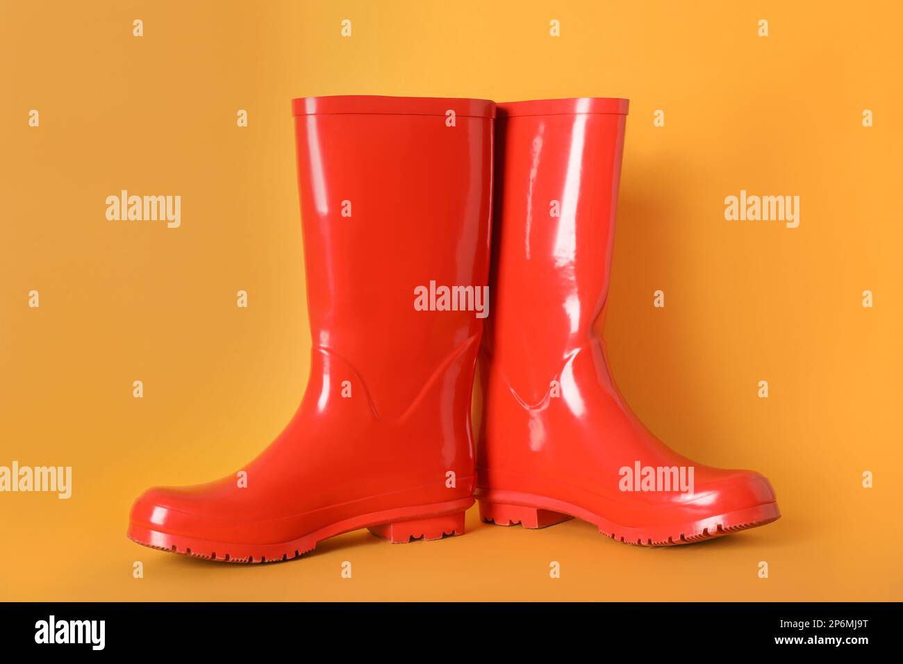 Pair of red rubber boots on orange background Stock Photo - Alamy