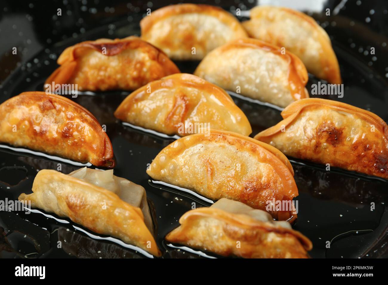 Cooking gyoza on frying pan with hot oil, closeup Stock Photo - Alamy
