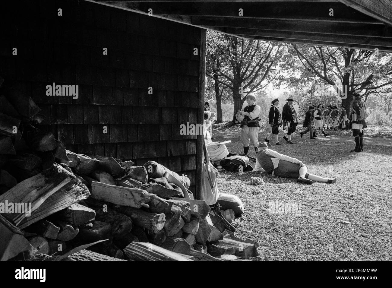 Actors in Colonial costumes and uniforms gather in the grass as viewed ...