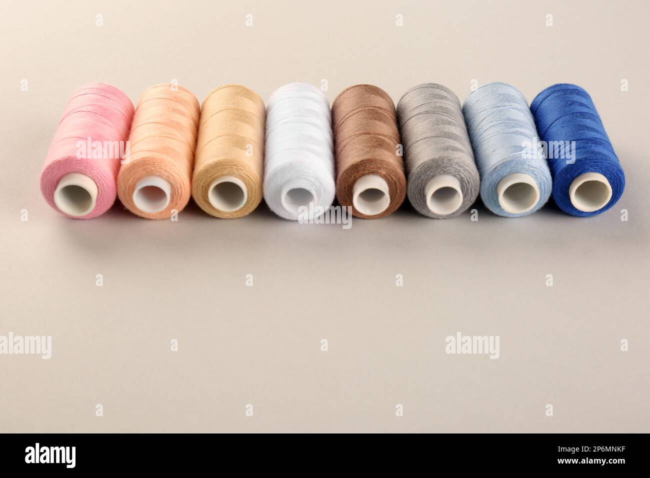 Different sewing threads on light grey background. Space for text Stock ...