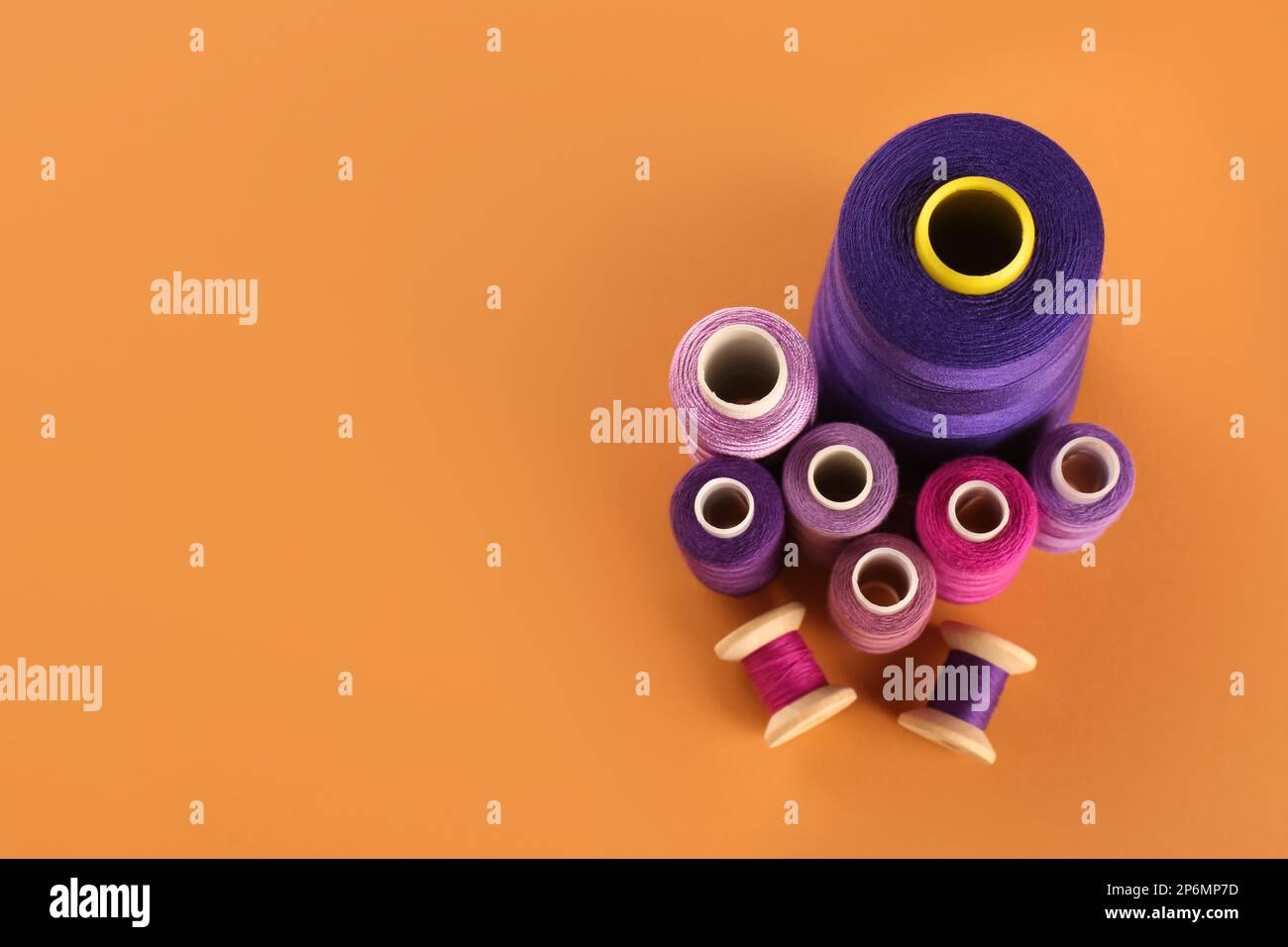Different shades of violet and purple sewing threads on orange ...