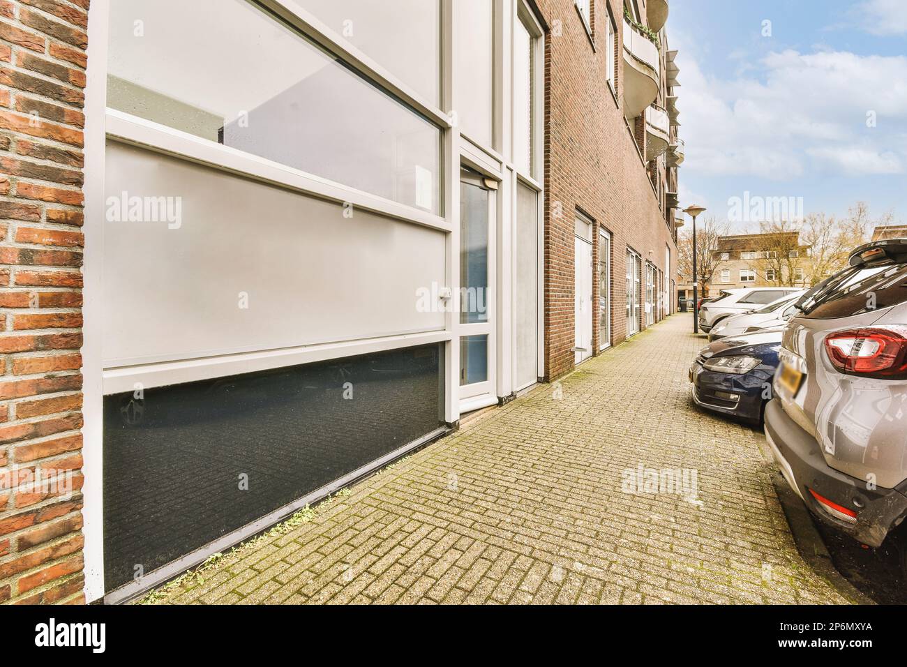 some cars parked on the side of a bricked street in front of a red ...